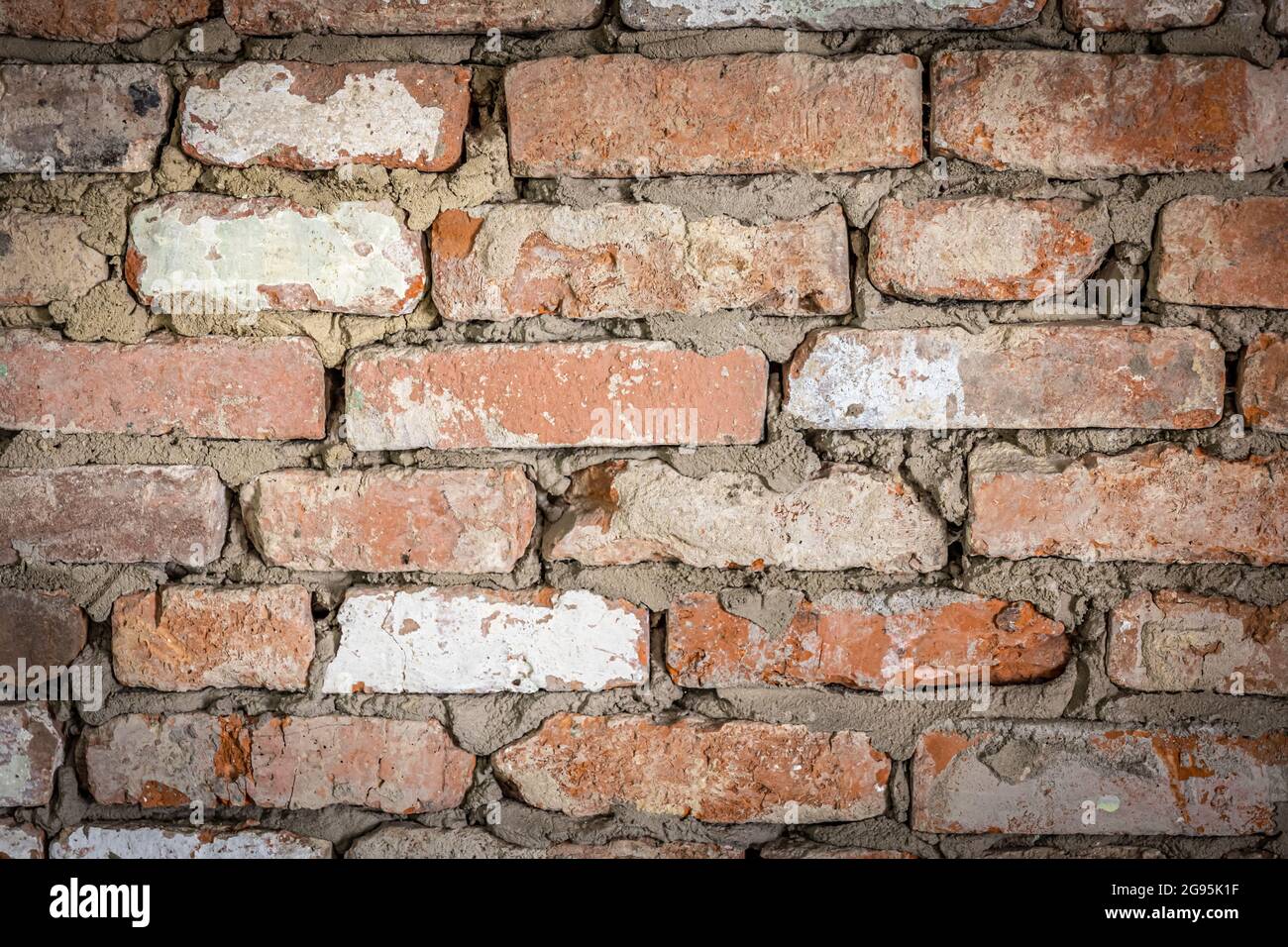 Wall of an old brick building with peeled plaster and painted surface ...