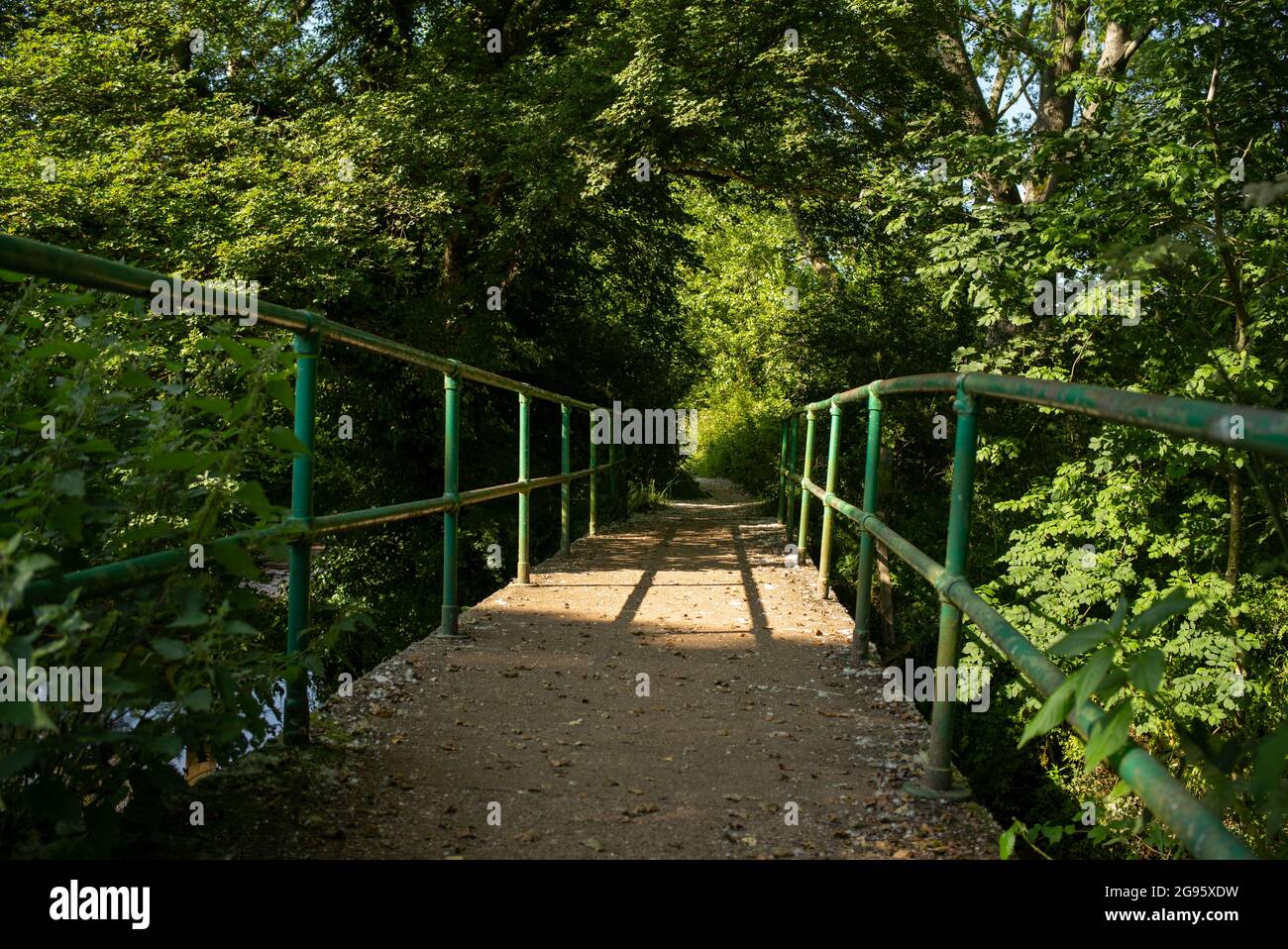A single track bridge crossing leading to an overgrown footpath with ...