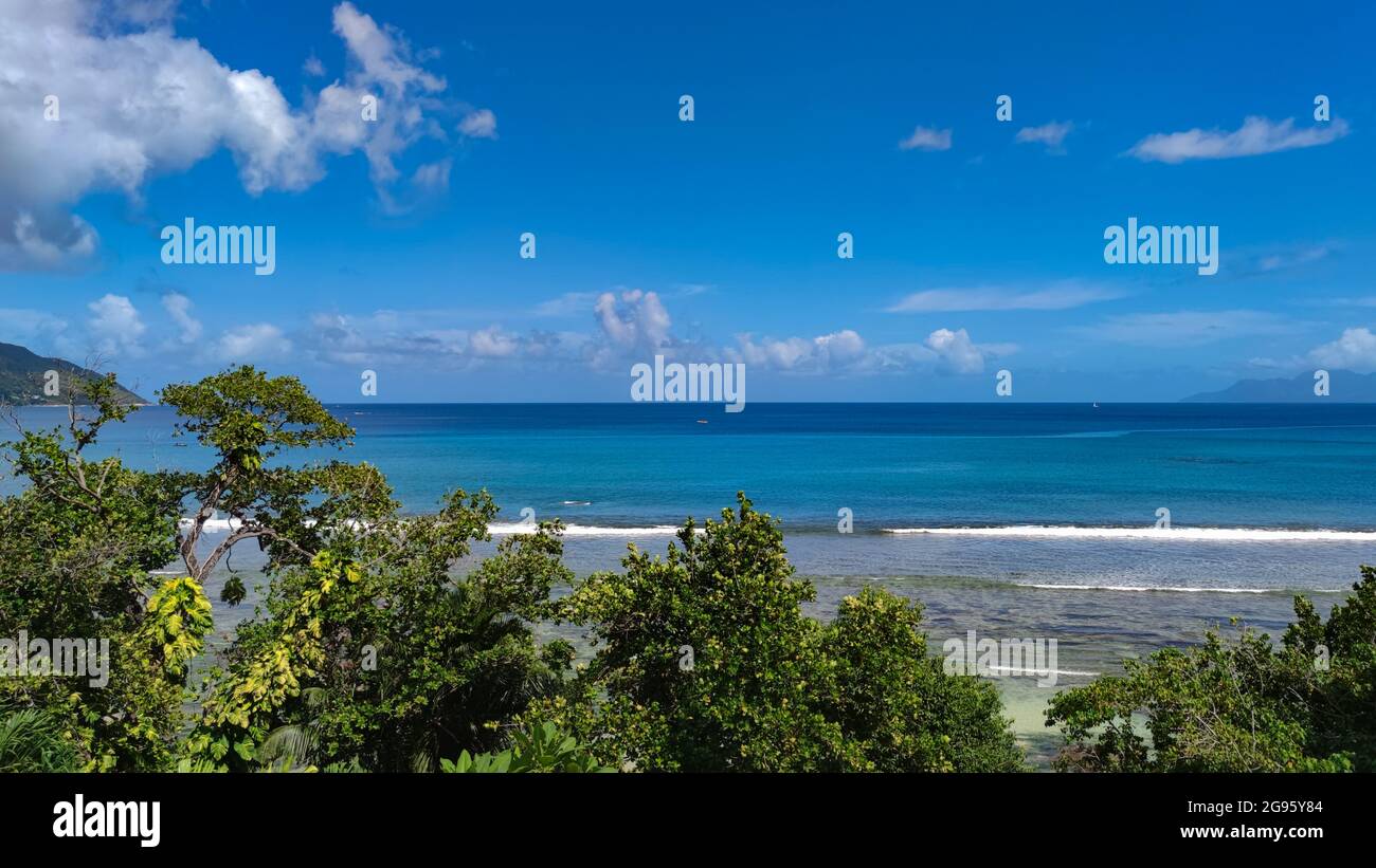 Calm Indian Ocean, green trees and bright sky, Seychelles Stock Photo ...