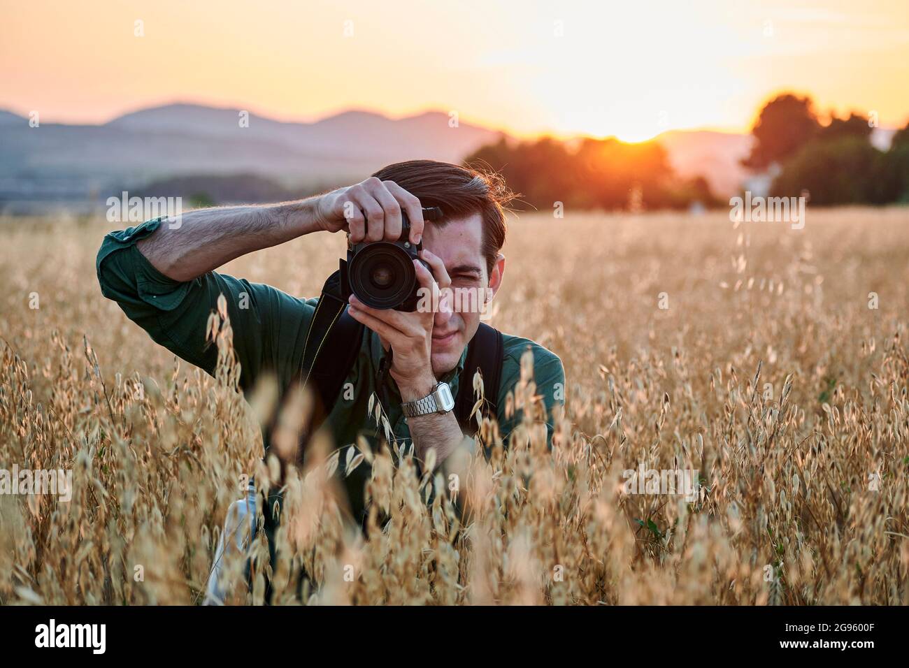Portrait of a photographer looking at camera in a meadow at sunset ...