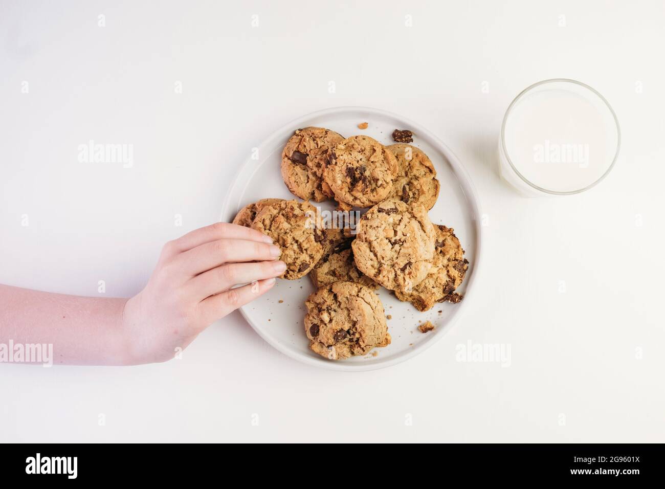 Hand taking chocolate chip cookie from a plate Stock Photo - Alamy