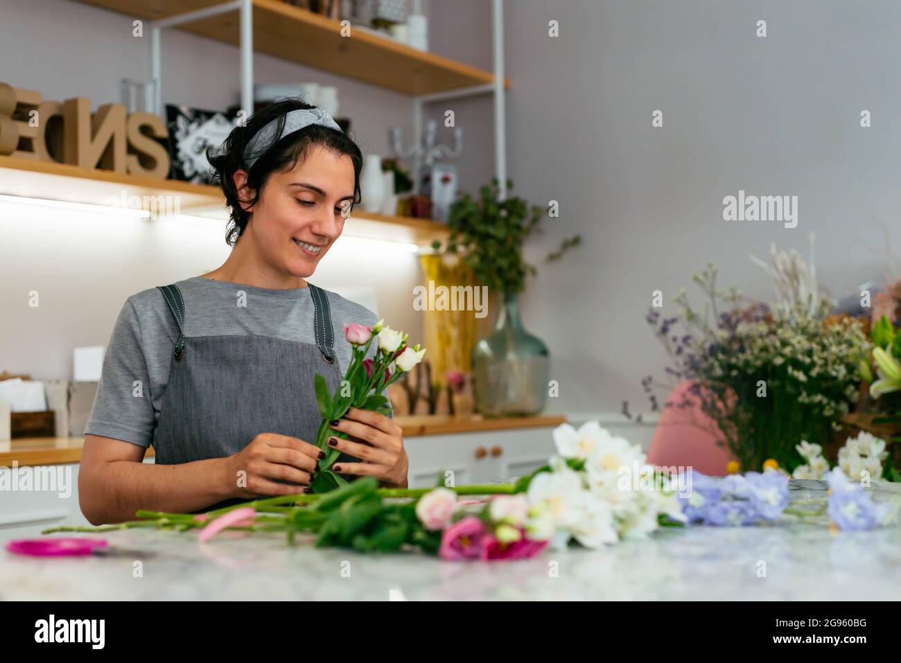 A young florist putting together a bouquet of flowers in her studio ...