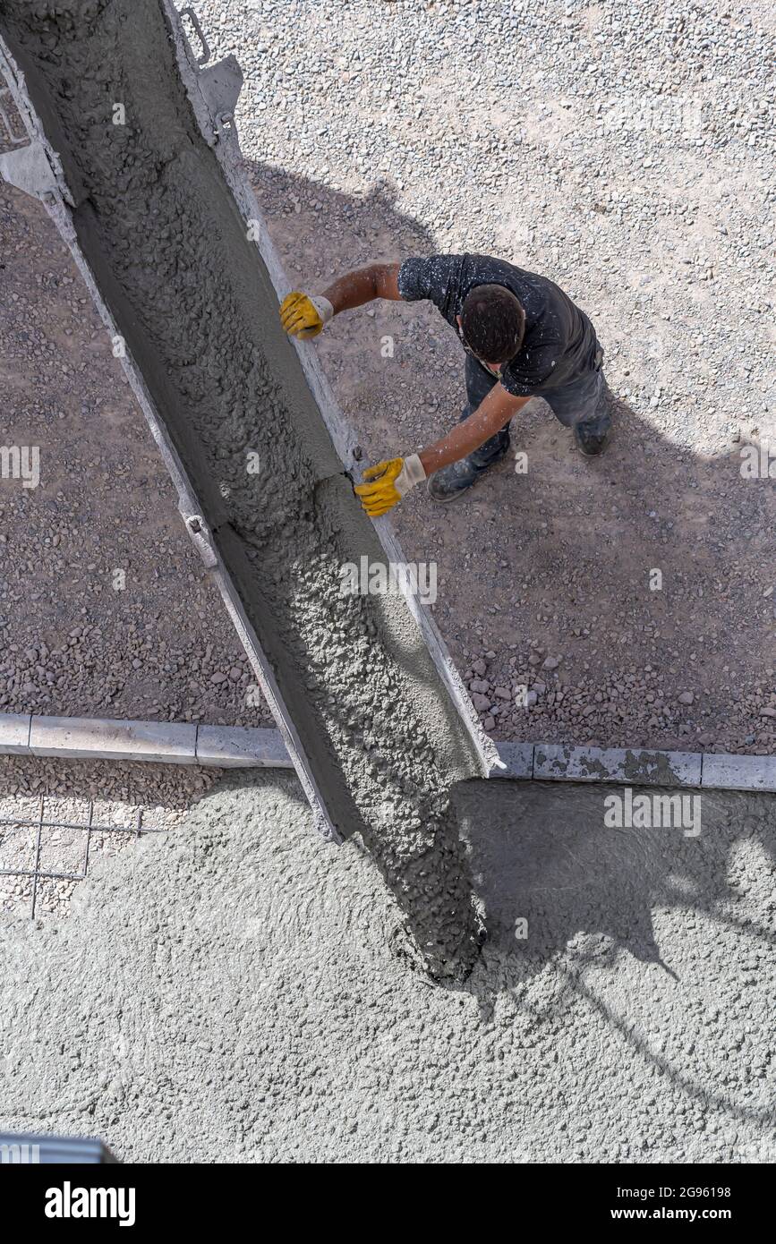 Vertical shot of a worker filling fresh concrete slab with a special ...