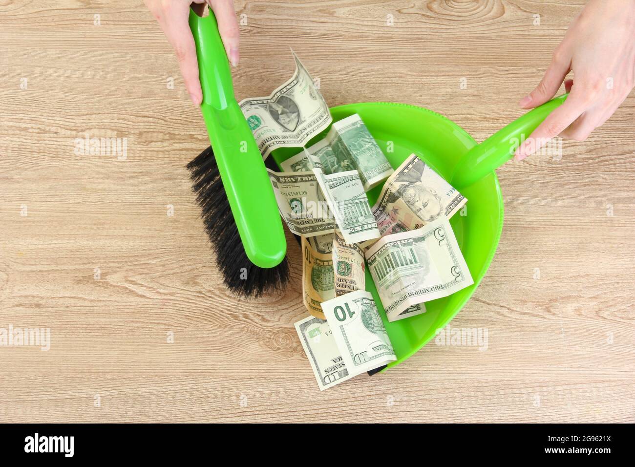 Sweeps money in the shovel on wooden background close-up Stock Photo ...