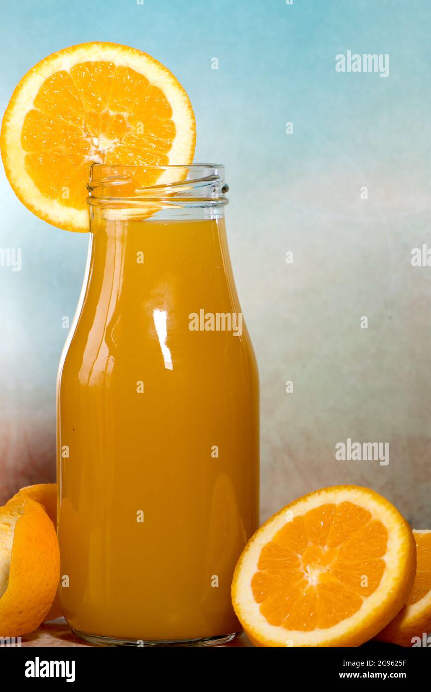 Fresh orange juice with orange slice in bottle glass on moody blue ...