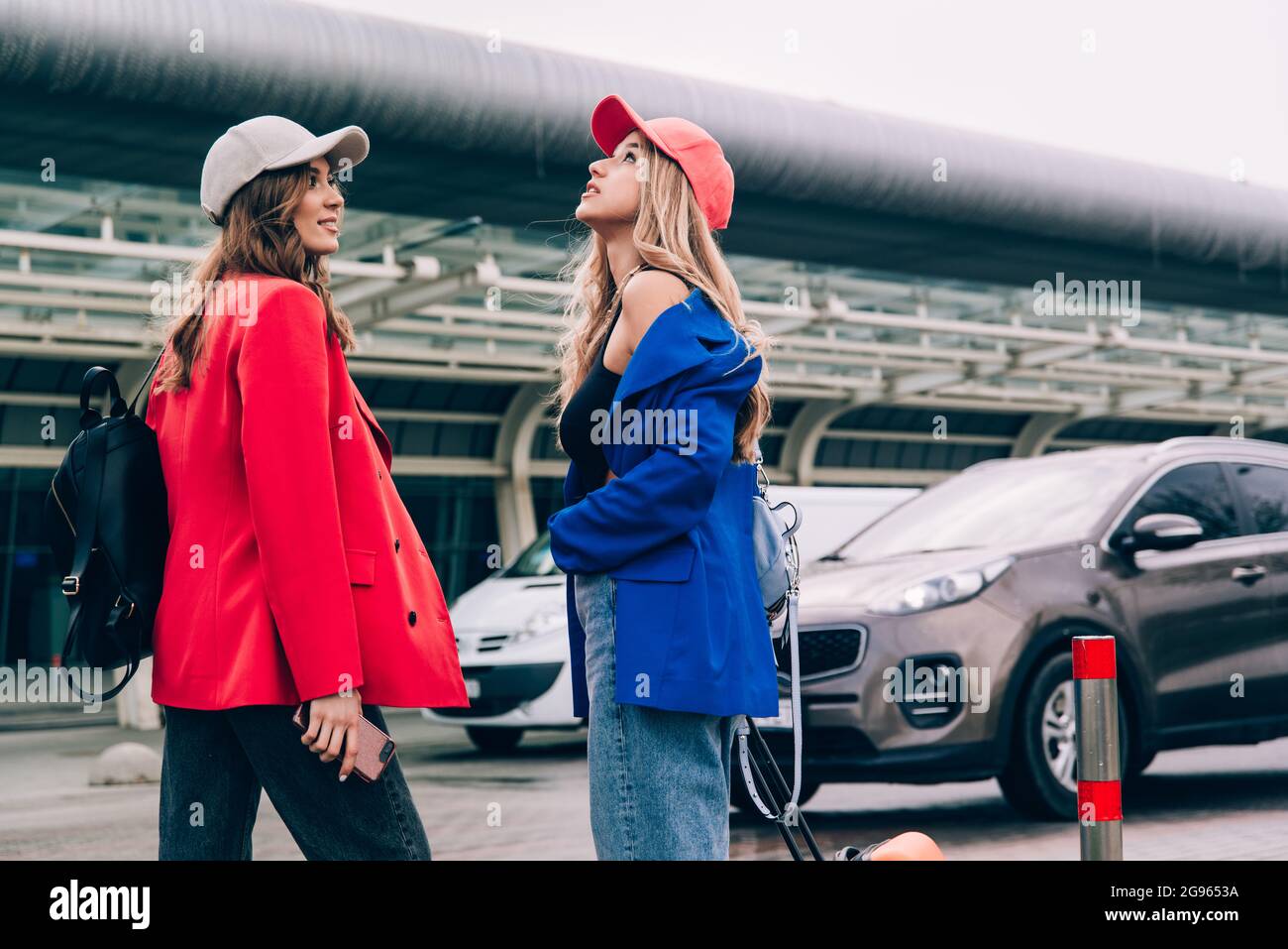 Two happy girls walking near airport, with luggage. Air travel, summer ...