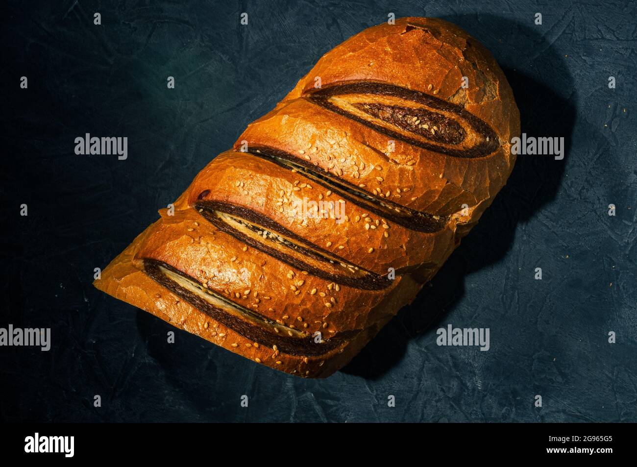 Unusual two-color fresh loaf of bread on a black background, photo in a ...