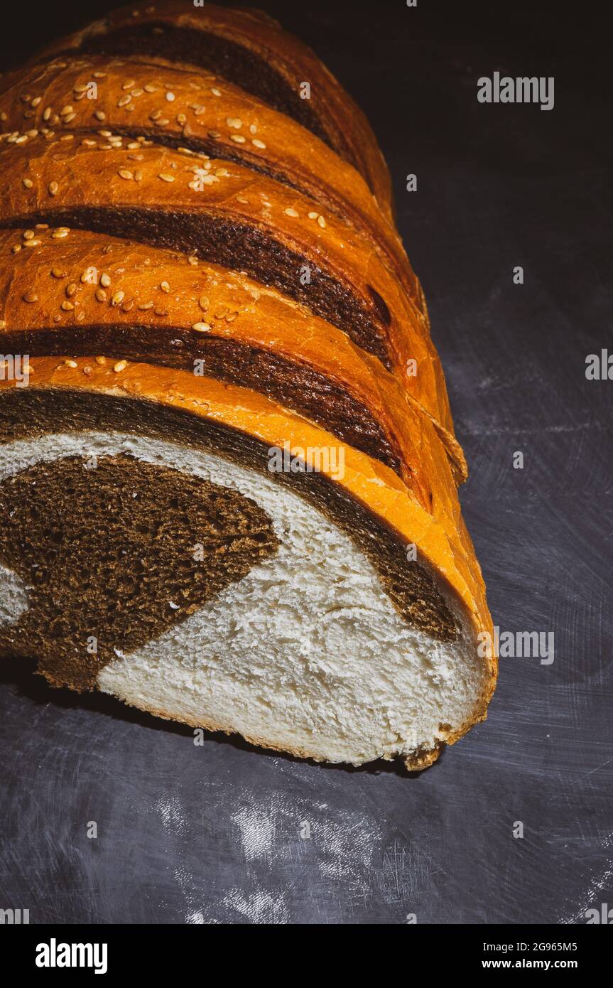 Unusual two-color fresh loaf of bread on a black background, photo in a ...