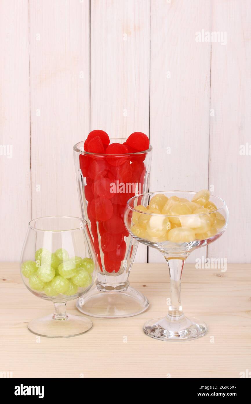 Color candies in glasses on wooden background Stock Photo - Alamy