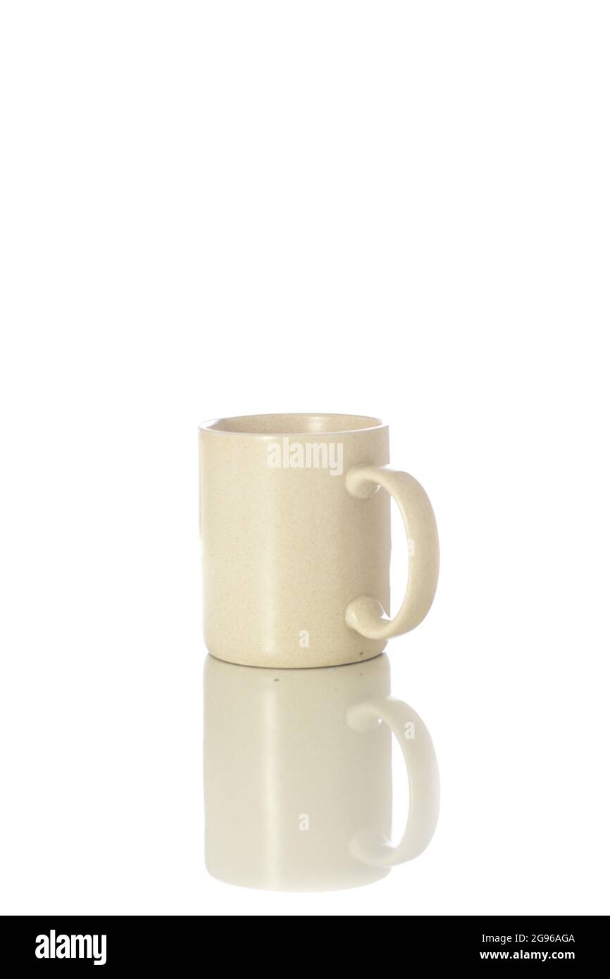 Vertical shot of a white mug on a reflective surface against a white ...
