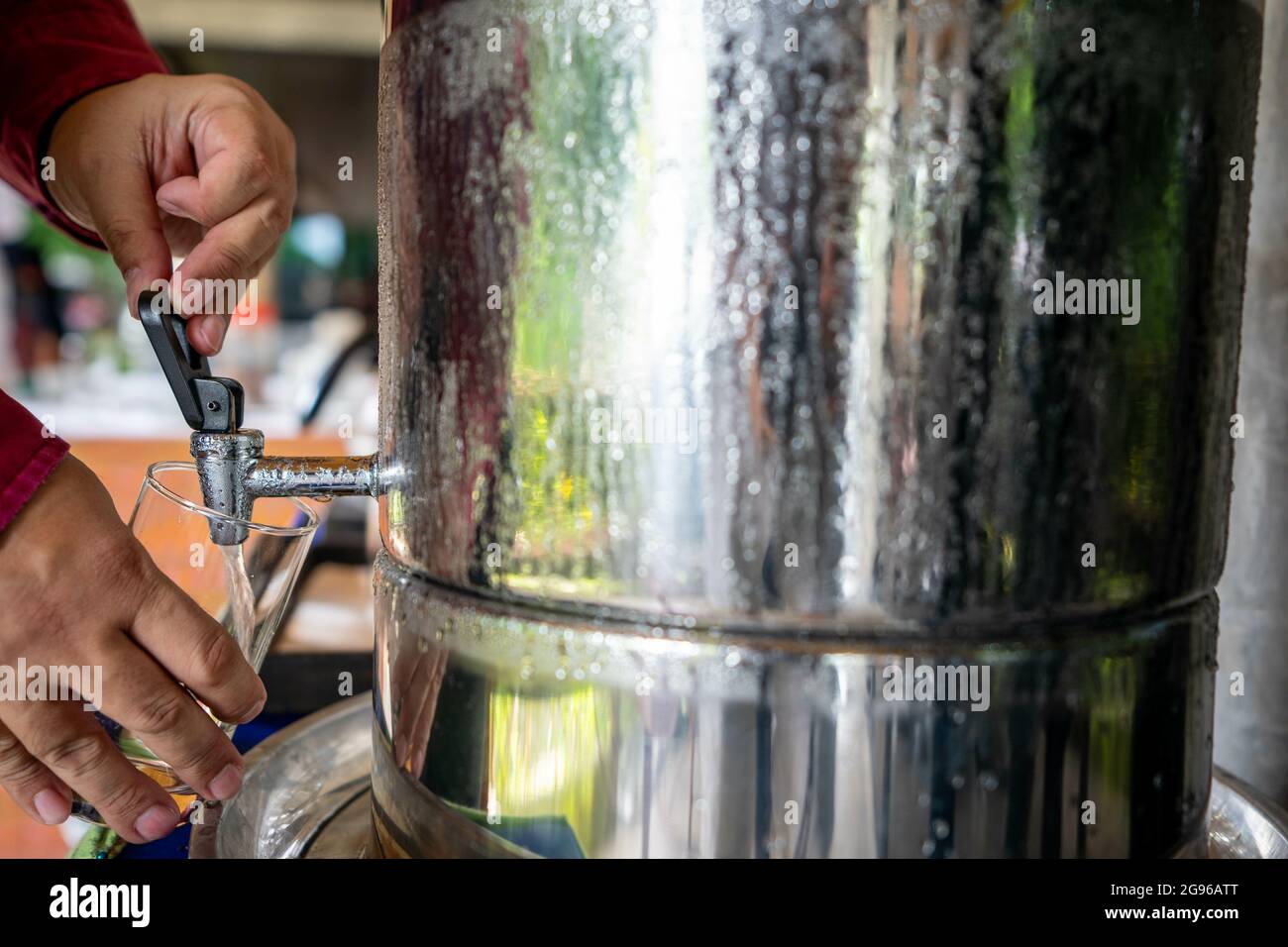 Closeup shot of a person tapping water from the ice-cold water tank ...