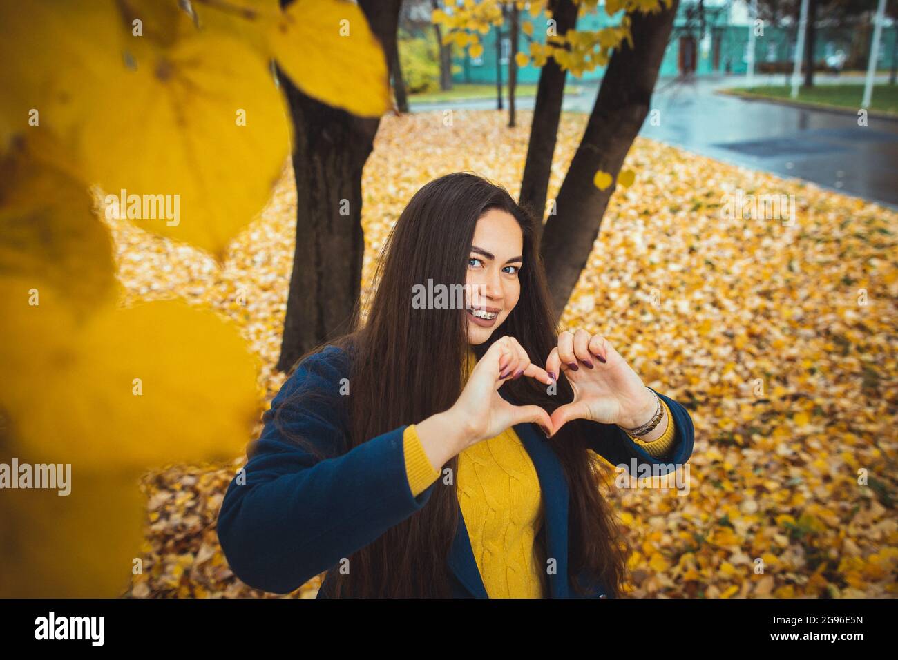 Playful young woman with autumn leaves in hand and fall yellow maple ...