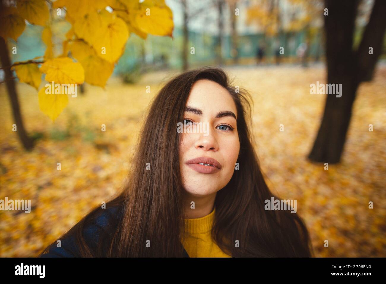 Playful young woman with autumn leaves in hand and fall yellow maple ...
