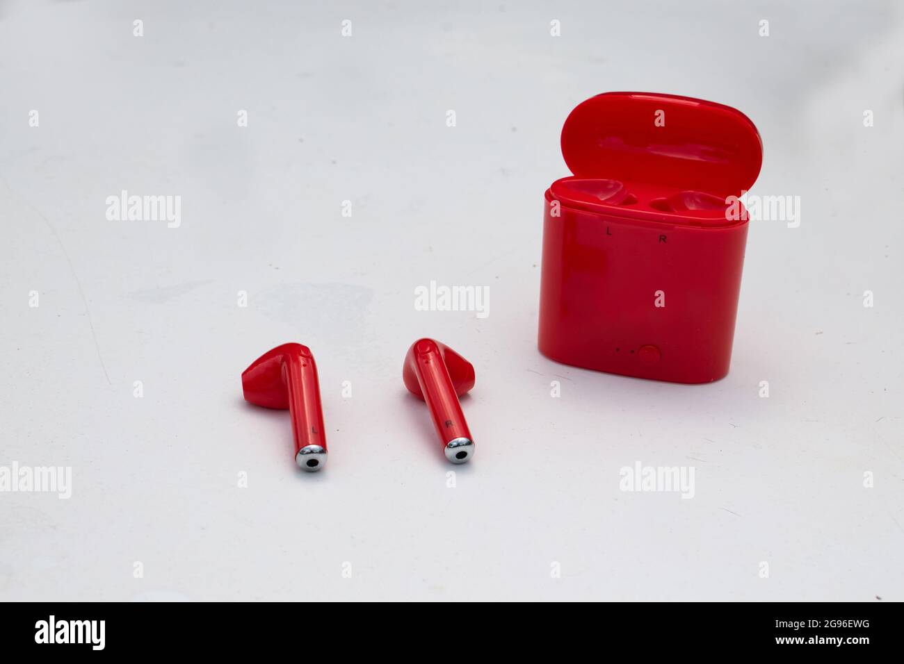 A pair of of bright red, wireless earbuds or headphones isolated on a ...