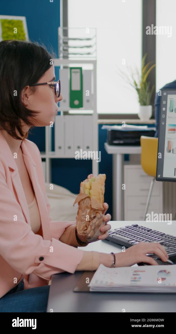 Businesswoman eating tasty sandwich having meal break working in ...