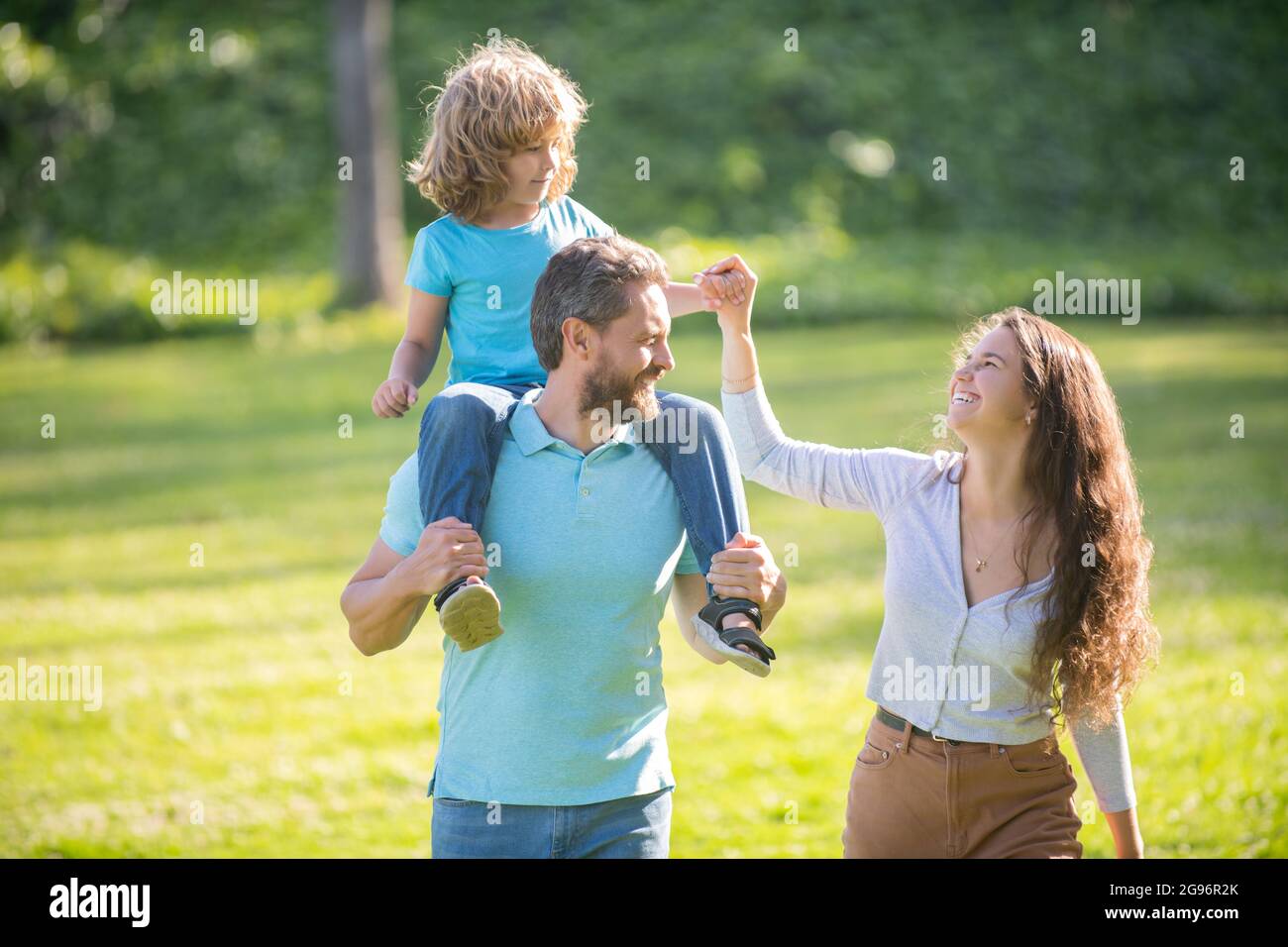 Happy foster family of mother and father carrying adoptive boy child on ...