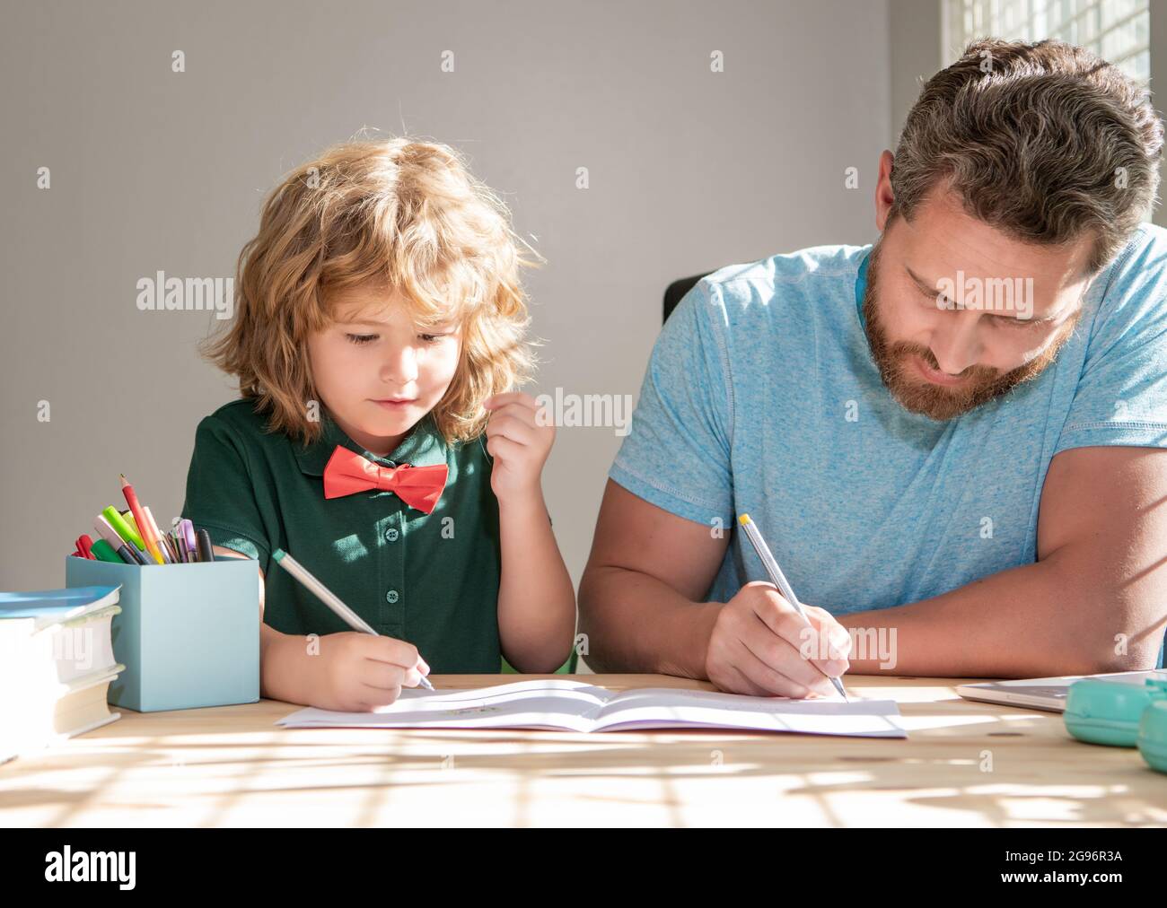 bearded father writing school homework with his kid son in classroom ...