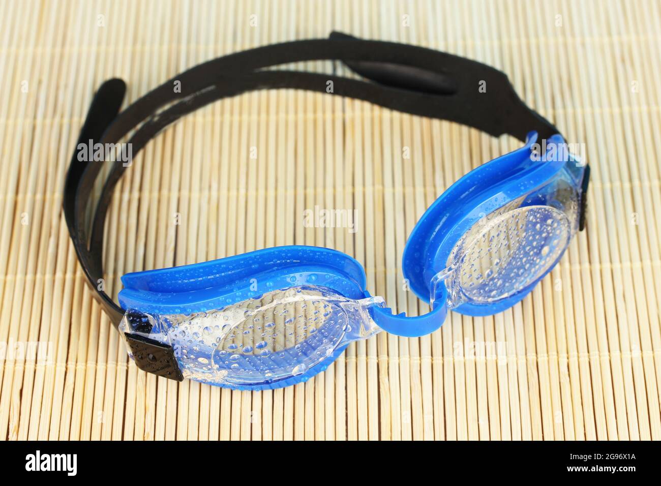 blue swim goggles with drops on a bamboo pad Stock Photo - Alamy