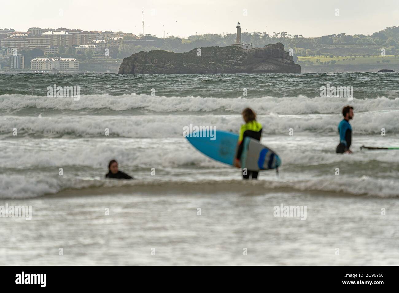 People walking with surfboards and surfing, in the city of Somo in the ...