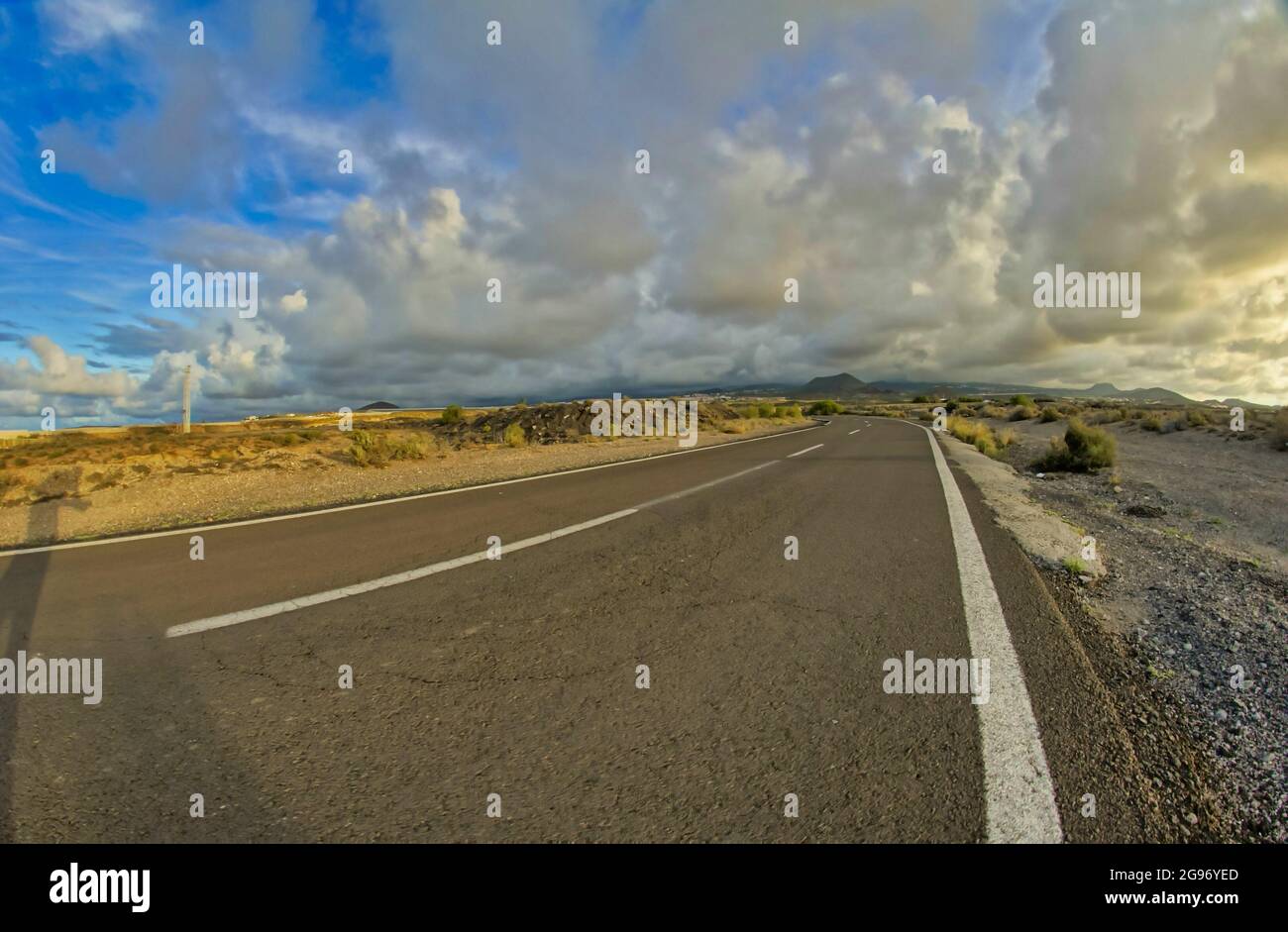 Shot of the asphalt-covered road surrounded by rocks and grass under a ...