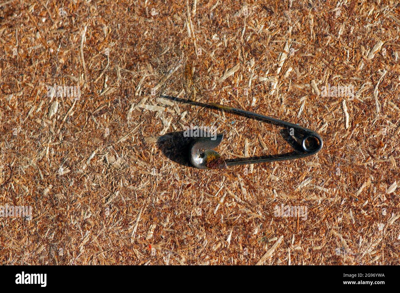 A rusty safety pin on particle board for wallpaper Stock Photo - Alamy