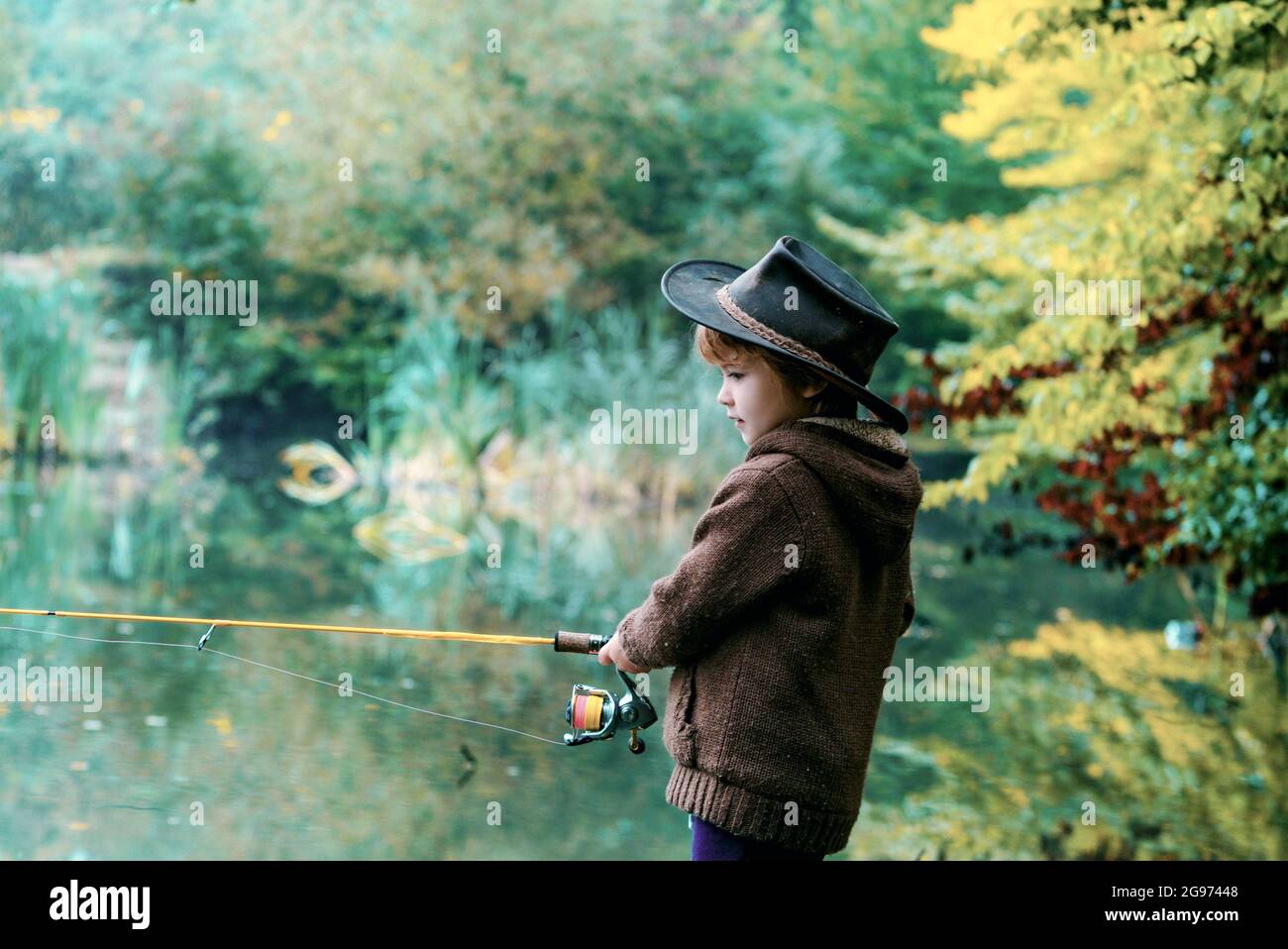Child learning how to fish, holding a rod on a lake. Kid with fishing ...
