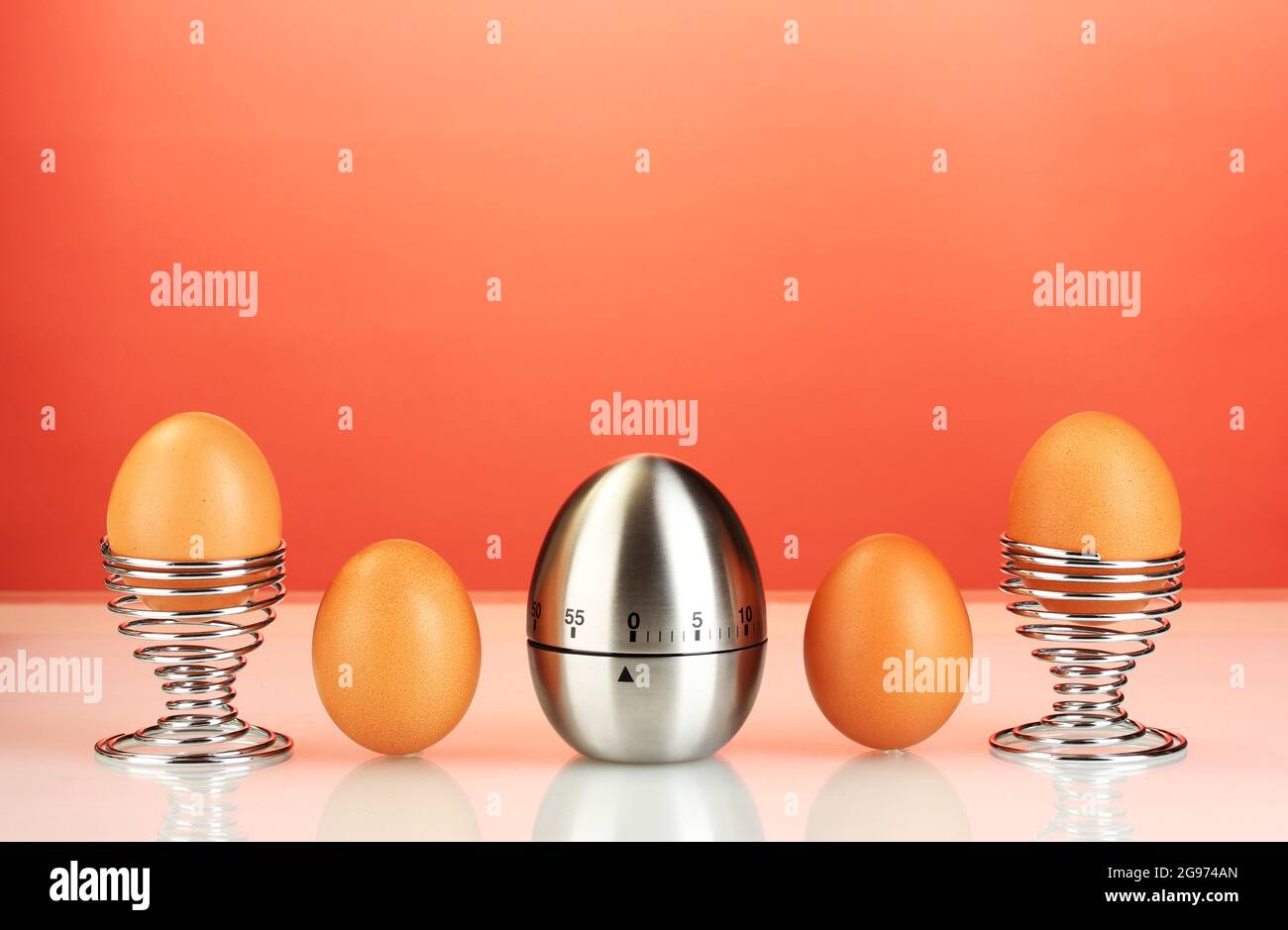 egg timer and eggs on red background Stock Photo - Alamy