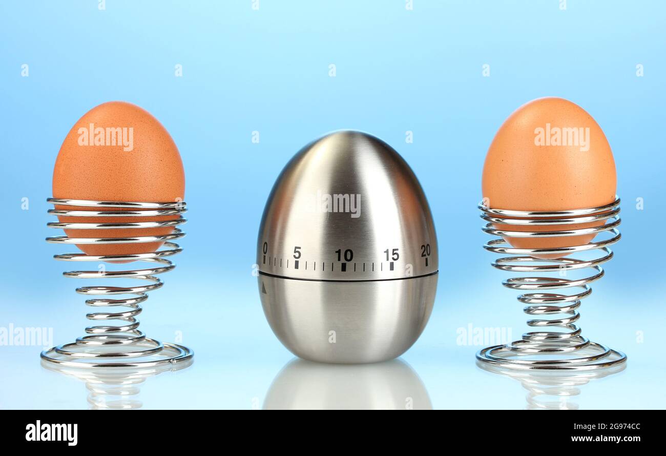 egg timer and egg in metal stand on blue background Stock Photo - Alamy