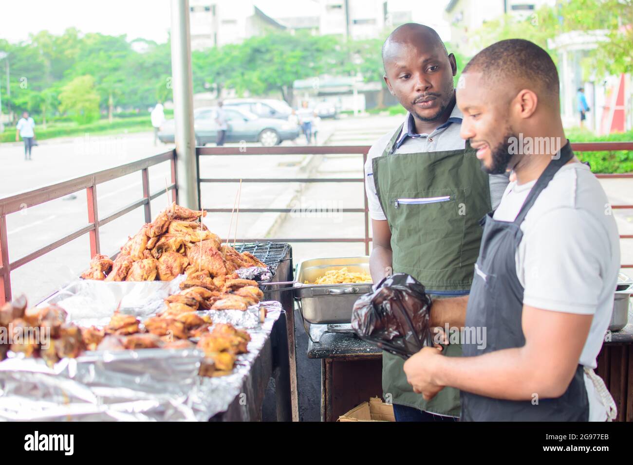 Two male African barbeque and roasted chicken sellers smiling and ...