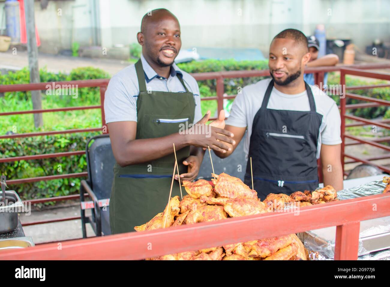 Two male African barbeque and roasted chicken sellers smiling and ...
