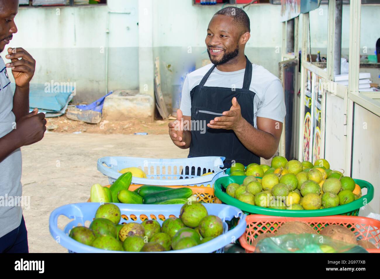 A male African grocery and fruit seller tying his apron in preparation ...