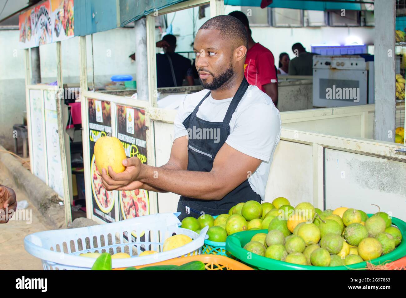 A male African grocery and fruit seller tying his apron in preparation ...