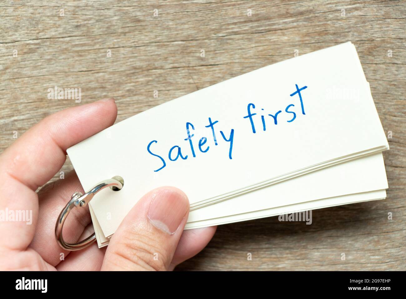 Man hold the flash card with handwriting word safety first on wood ...
