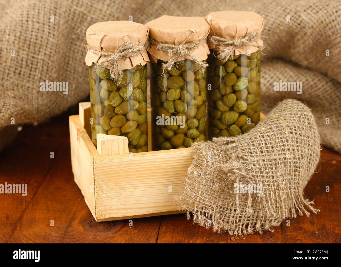 Glass jars with tinned capers on sack background close-up Stock Photo ...