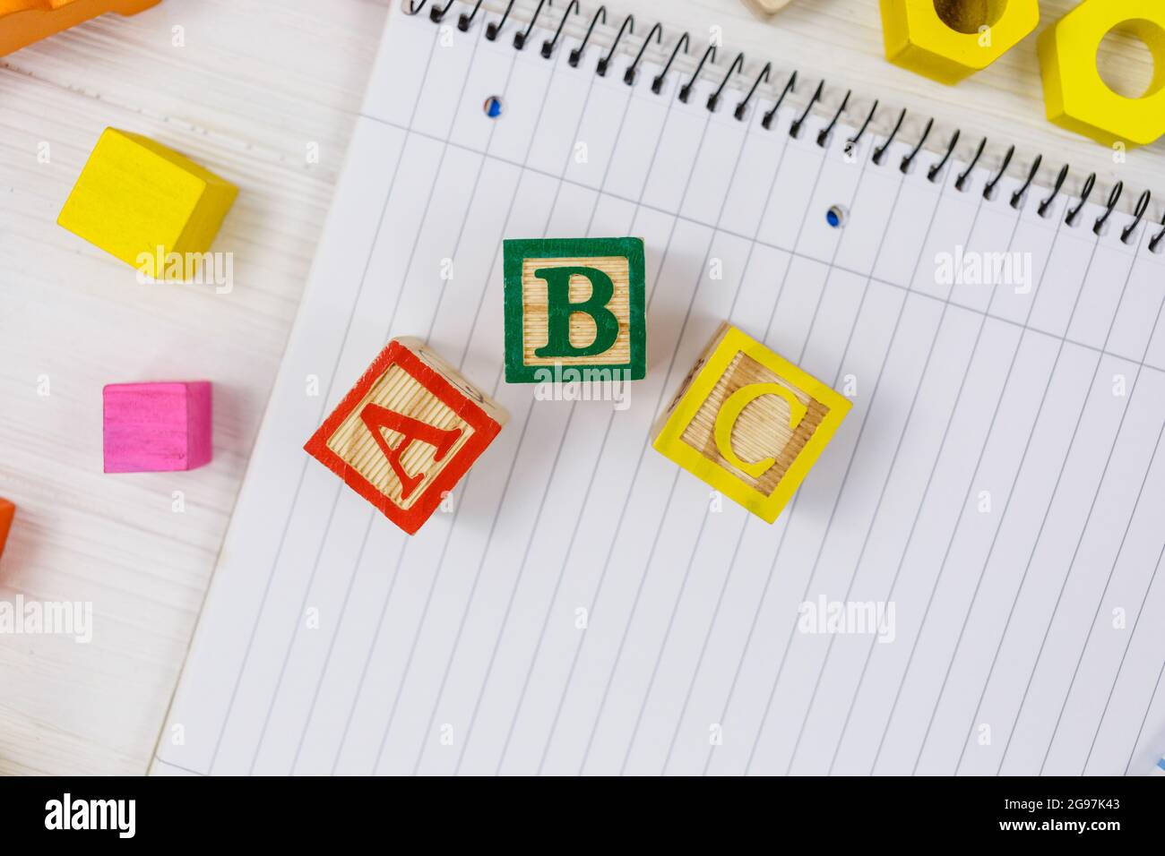 Wooden blocks spell out ABC, open notepad on wooden table. Games and ...