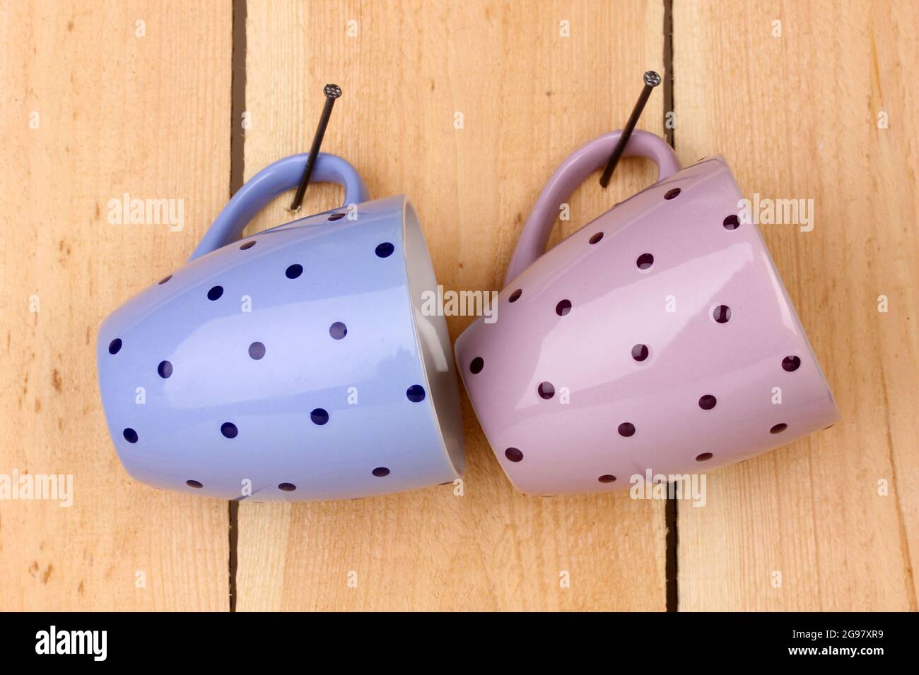 Nice cups hanging on nails on wooden background Stock Photo - Alamy