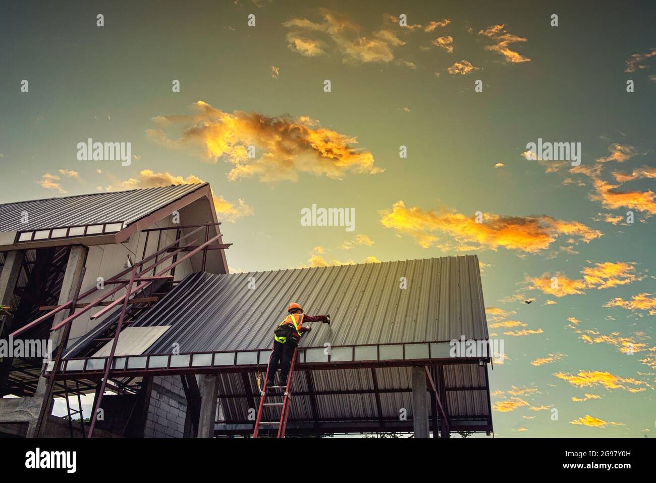 Worker man building tradesman on the roof of a house with safety helmet ...