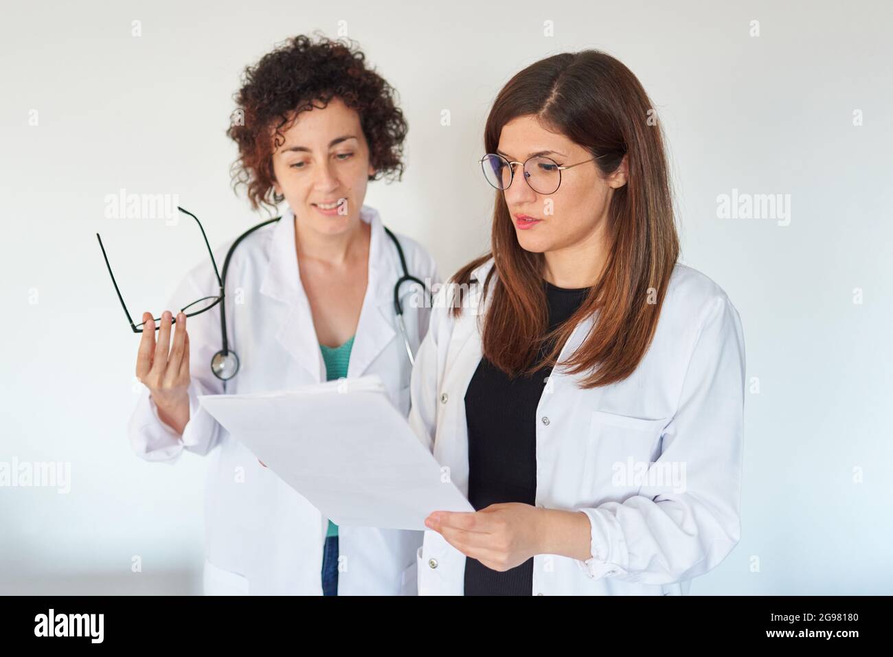 Two female doctors look at documents and discuss a diagnosis Stock ...