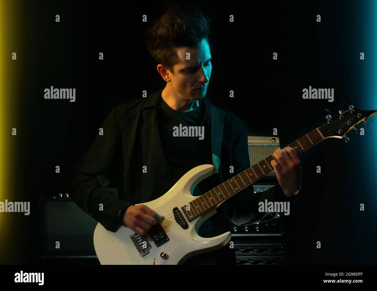 Handsome young male musician with electric guitar in recording studio ...