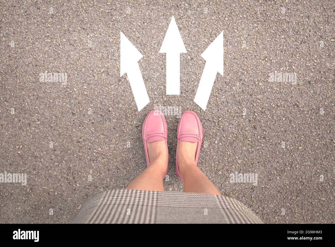 Woman legs in pink shoes standing on asphalt road with three direction ...