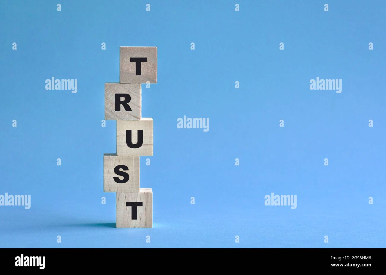 Trust word written on wooden blocks stacking up. Blue background with ...