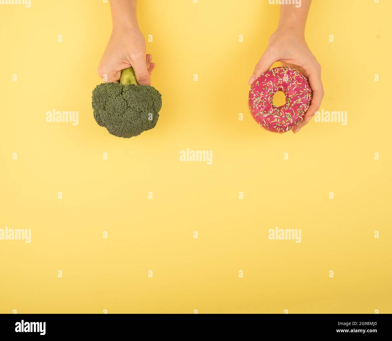 Comparison of eating habits. Woman holding broccoli and donut on a ...