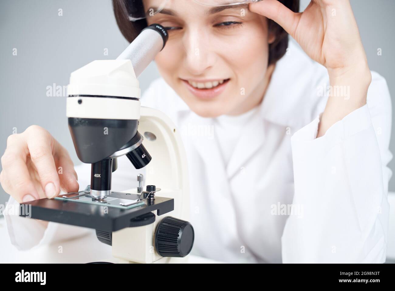 a scientist in a white coat looking through a microscope close-up ...