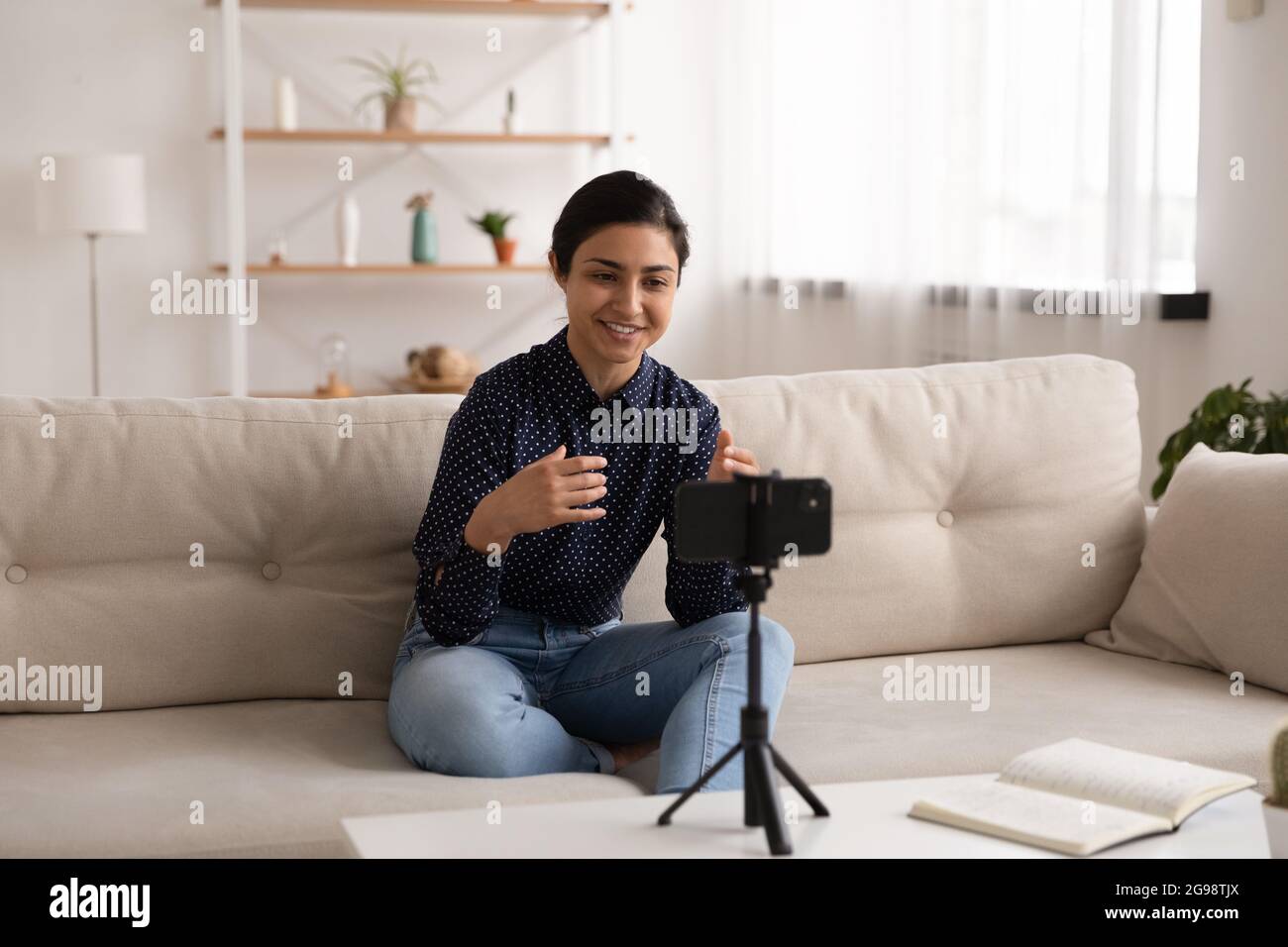 Smiling Indian woman recording video on smartphone on tripod Stock ...