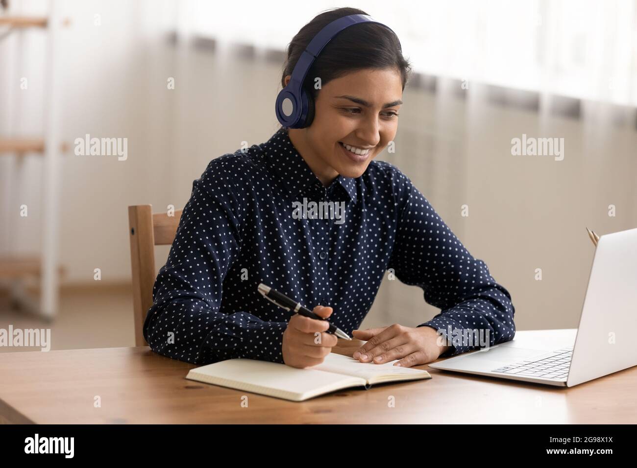 Close up smiling Indian woman in headphones taking notes Stock Photo ...