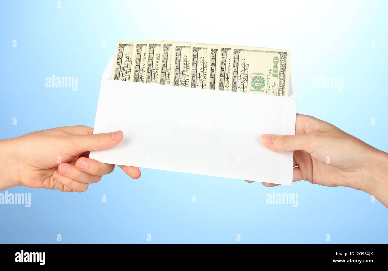 Woman's hand passes the envelope with the salary on blue background ...