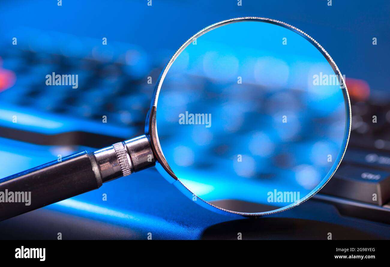 Magnifying glass on laptop keyboard in neon light Stock Photo - Alamy