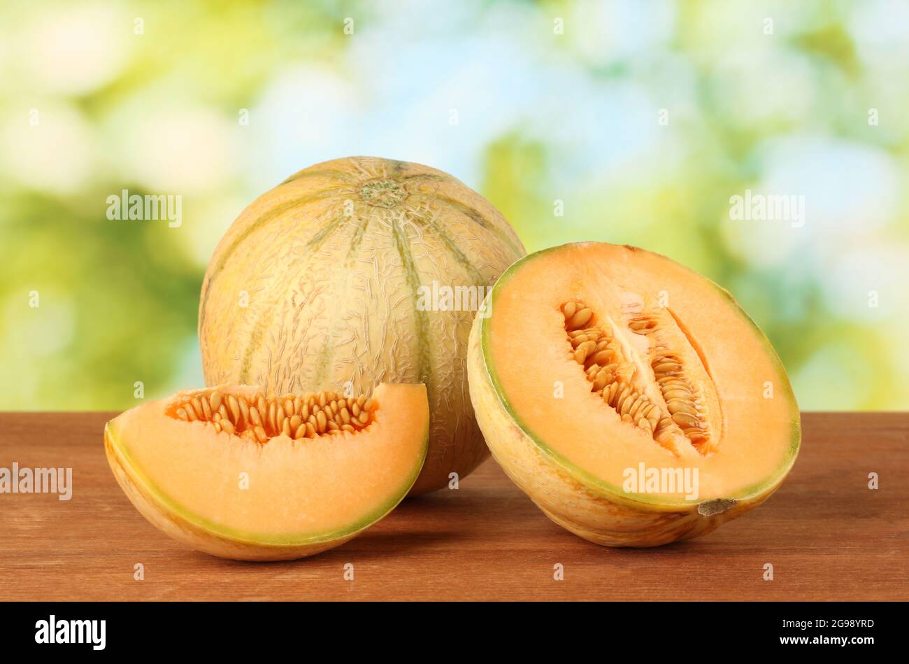 Cut melon on wooden table on green background Stock Photo - Alamy