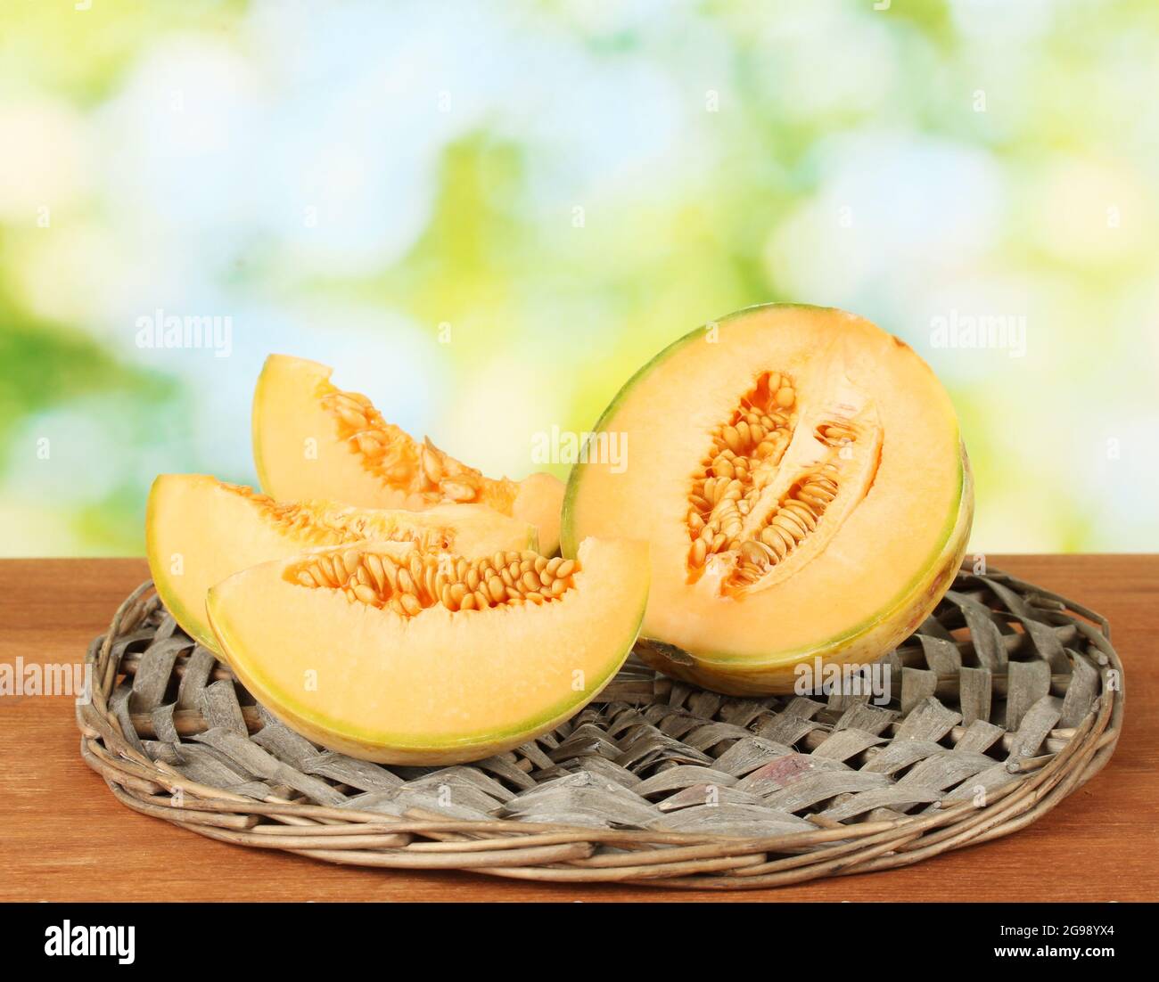 cut melon on wicker mat on green background close-up Stock Photo - Alamy