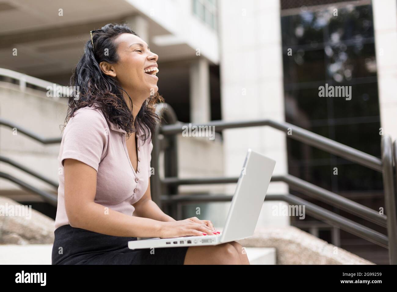 Young latin american woman very smiling outdoors. She is sitting using ...